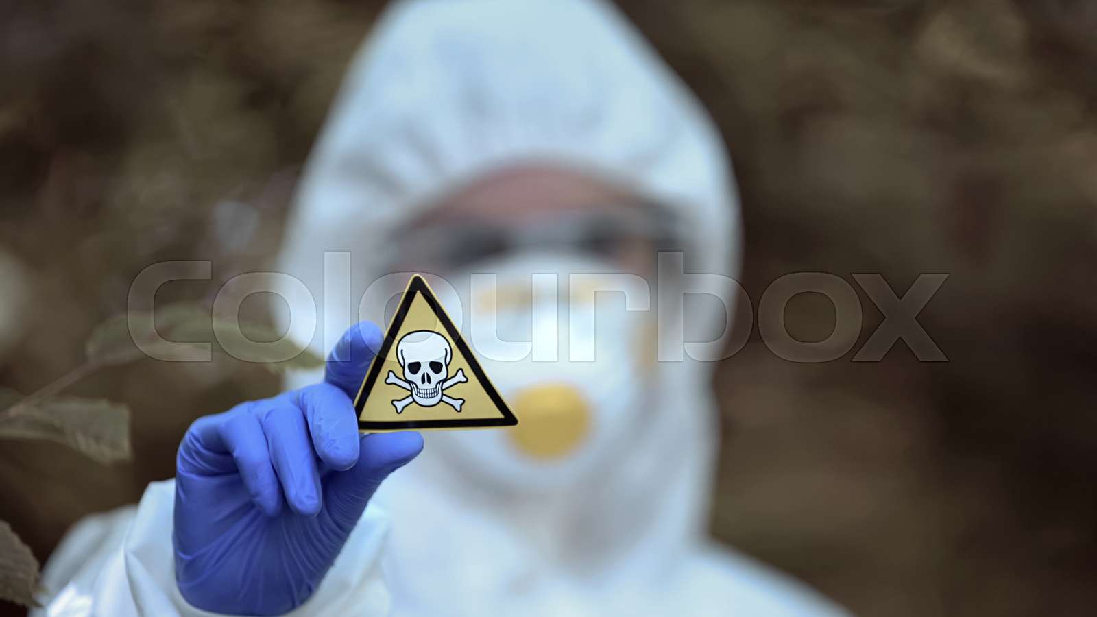 Female lab worker holding poison sign standing forest, dangerous level ...
