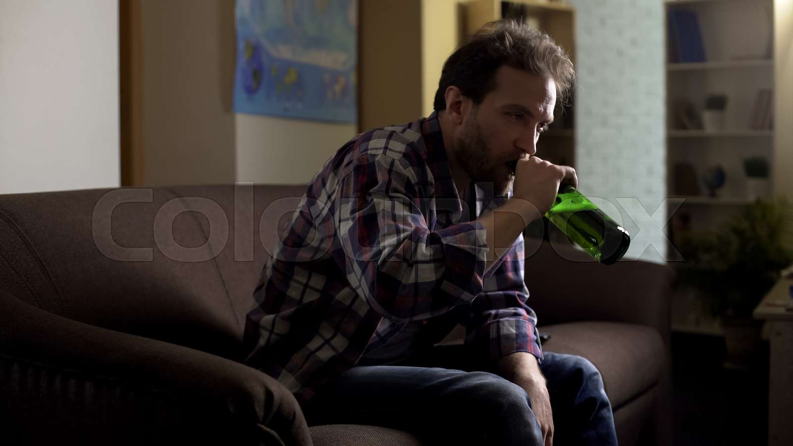 Drunken man sitting on sofa and drinking bottled beer, alcoholism and ...