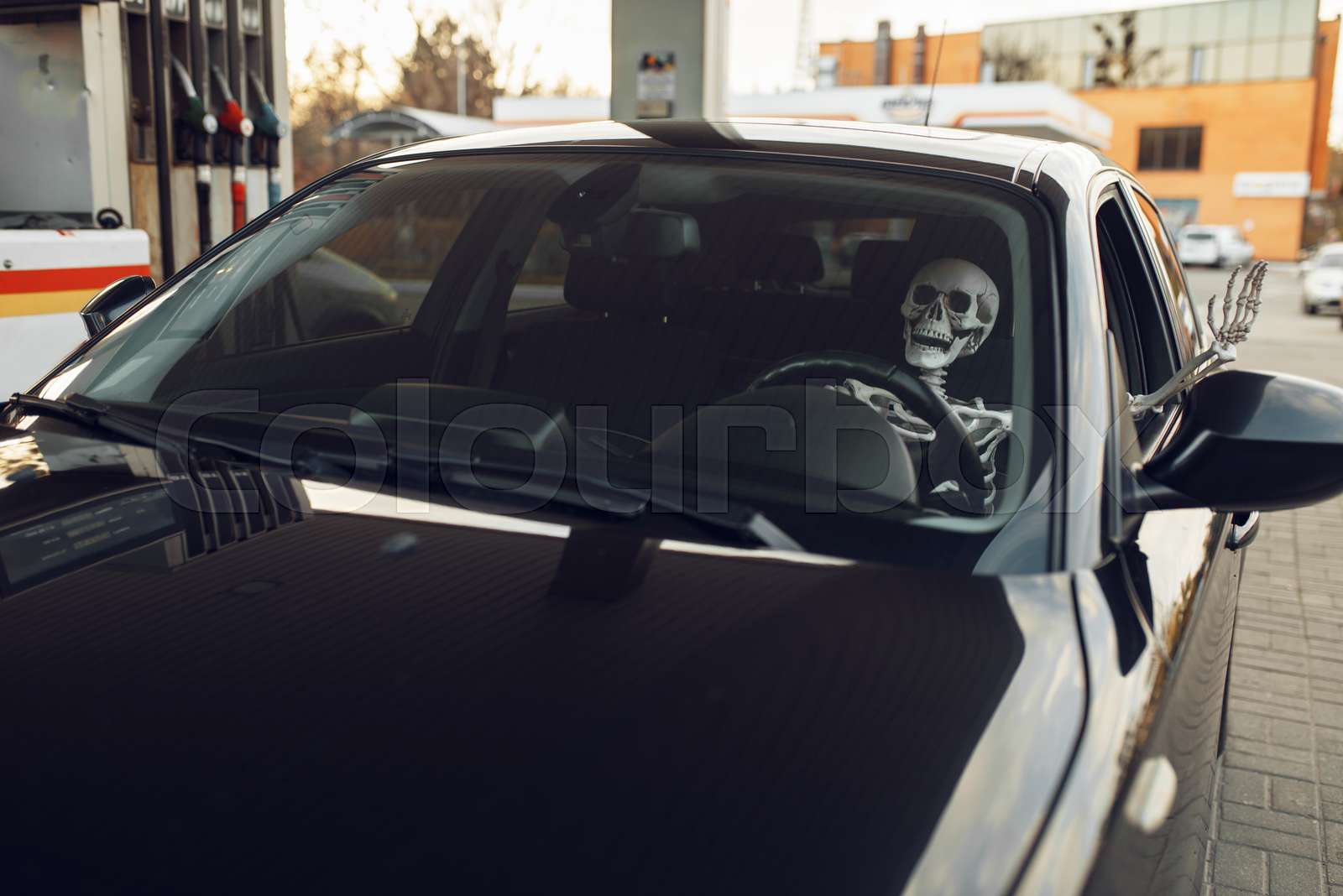 Skeleton in car, fueling on gas station | Stock image | Colourbox