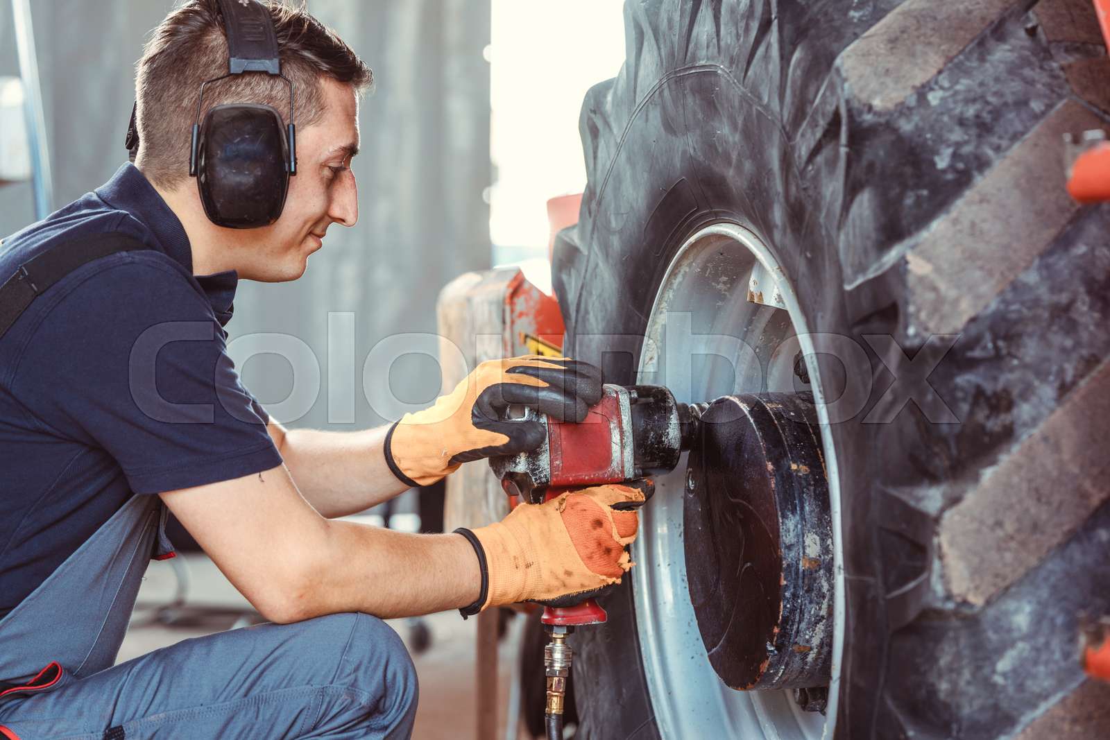 Farm machine mechanic working on wheel | Stock image | Colourbox