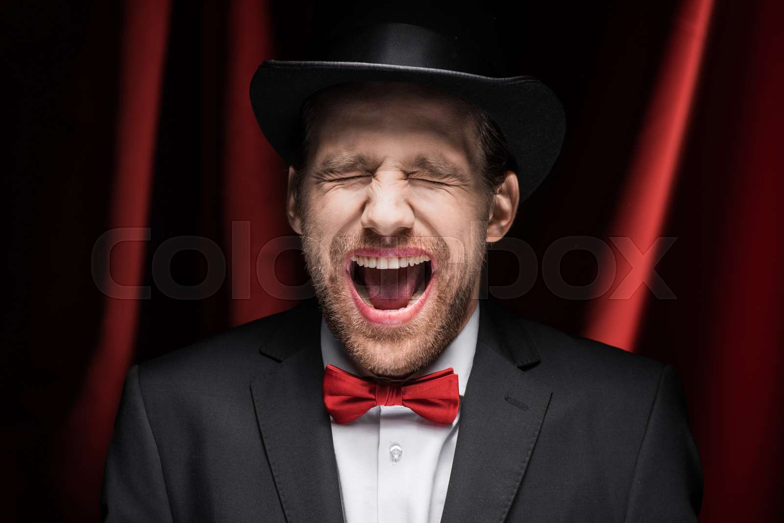 scary emotional magician with closed eyes and open mouth in circus with ...