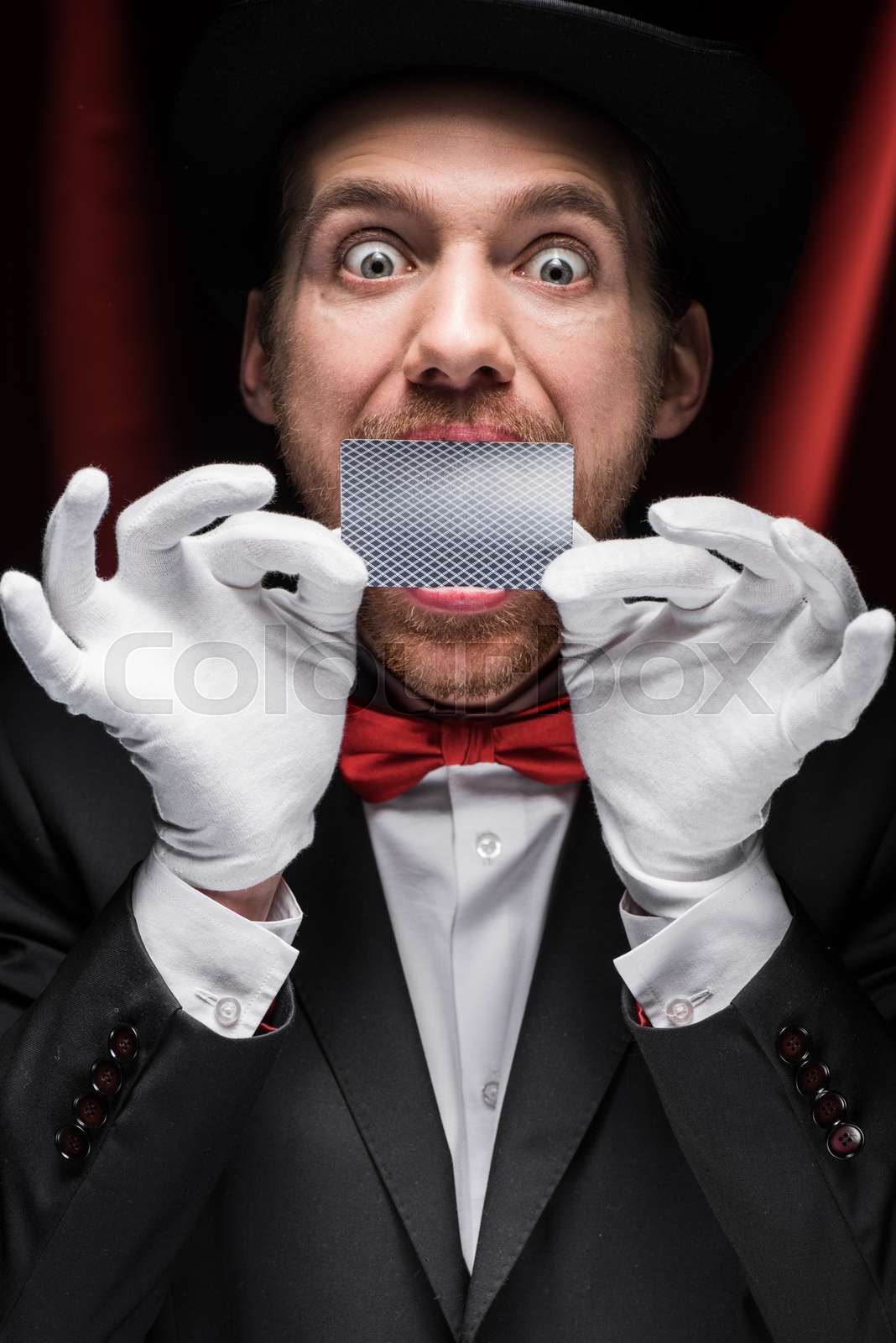 scary magician showing trick with playing card in circus with red ...
