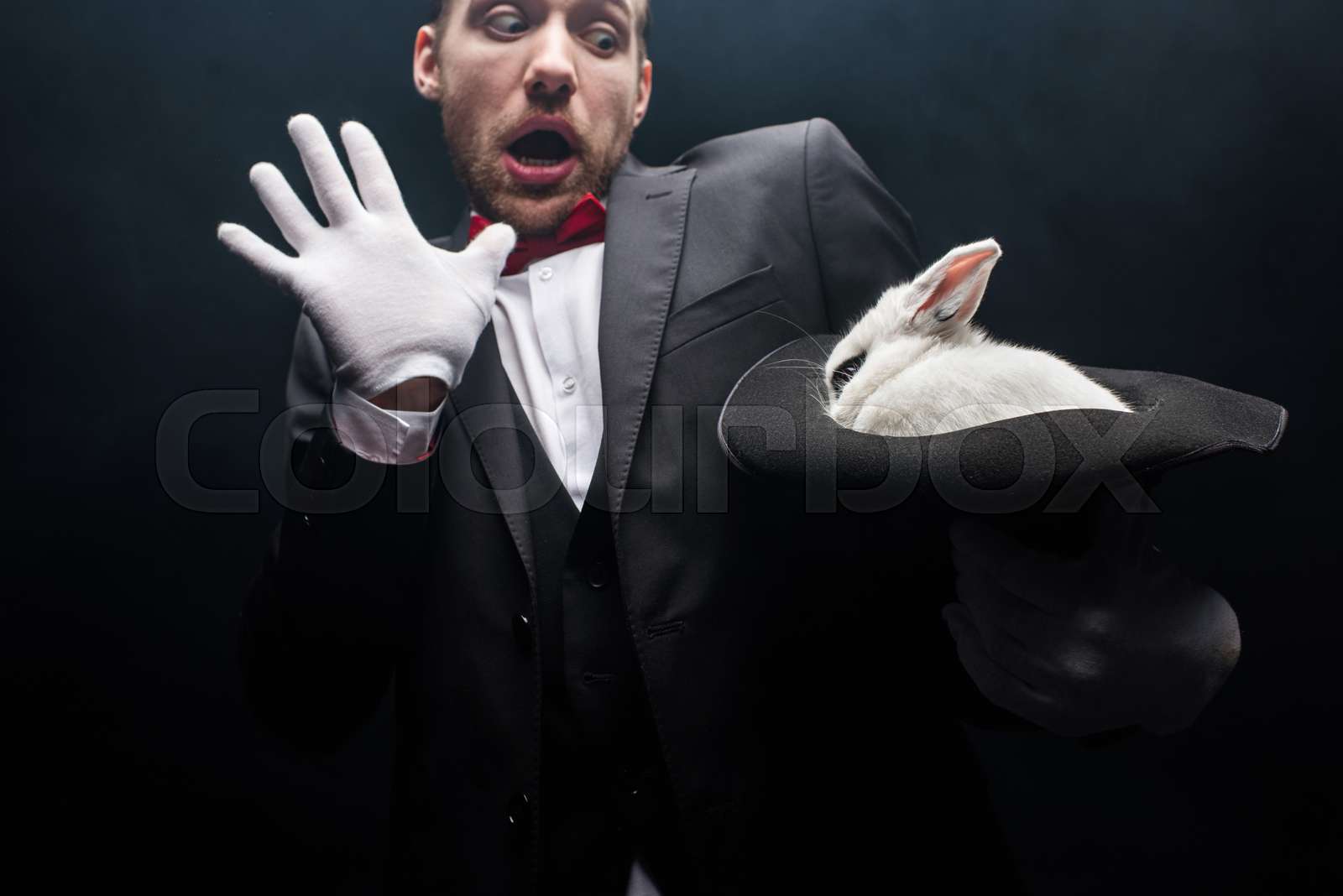 scared magician holding white rabbit in hat, isolated on black | Stock ...