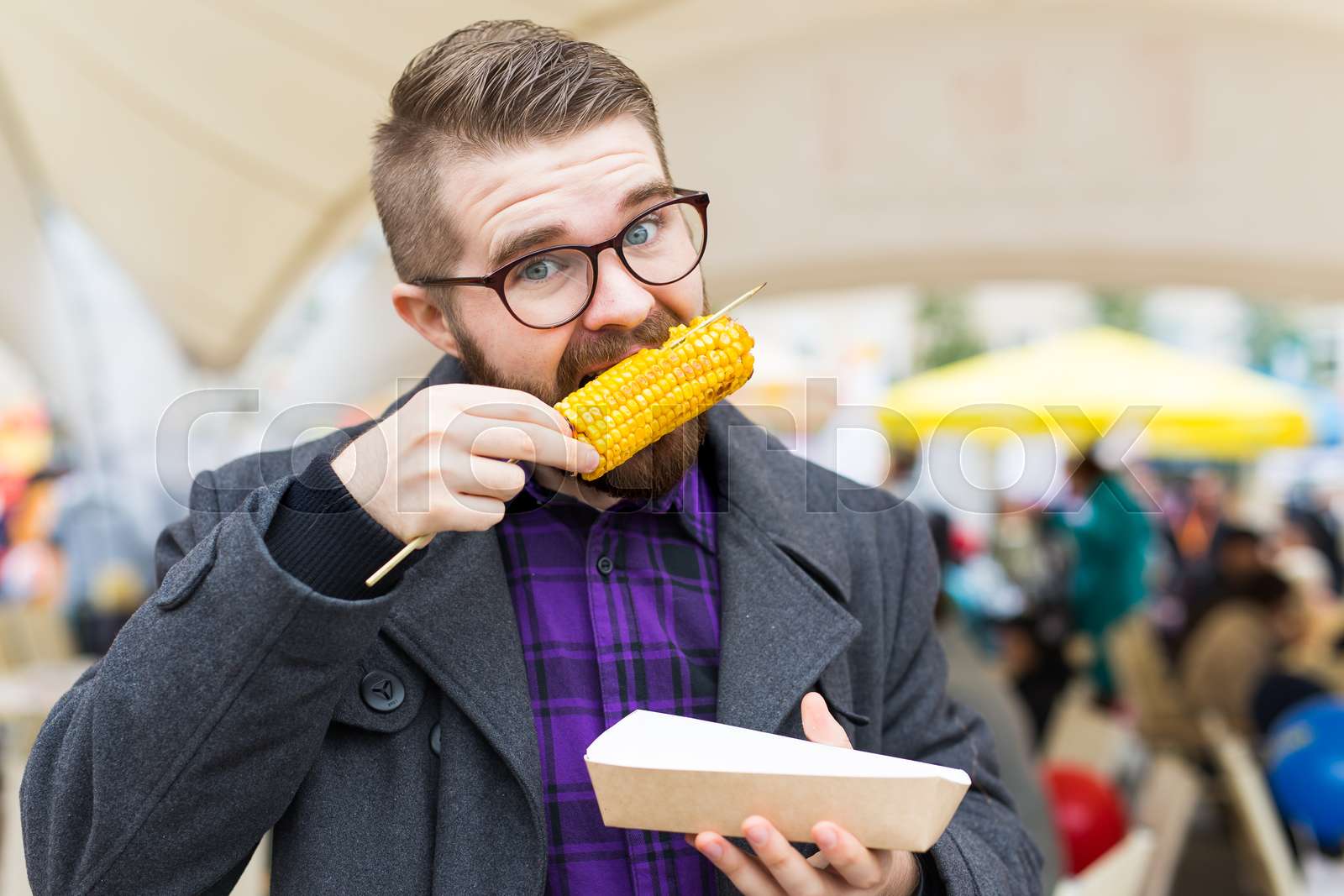 Handsome man eating roasted corn on the street. | Stock image | Colourbox