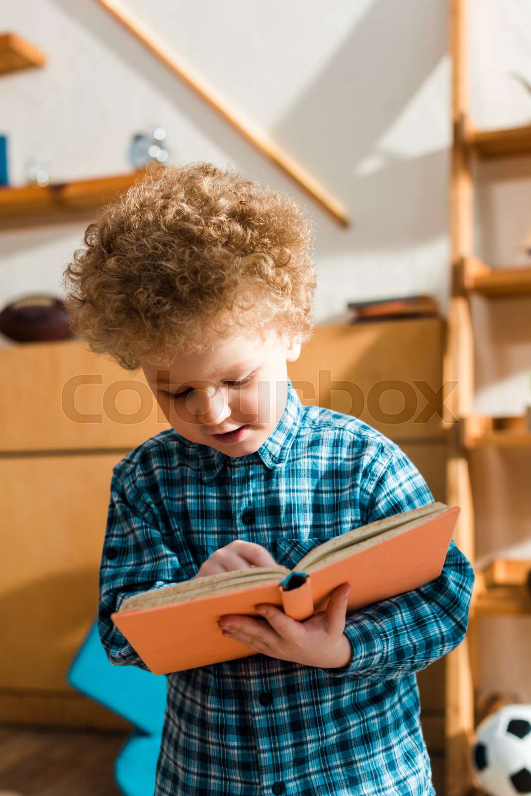 smart child smiling while reading book | Stock image | Colourbox