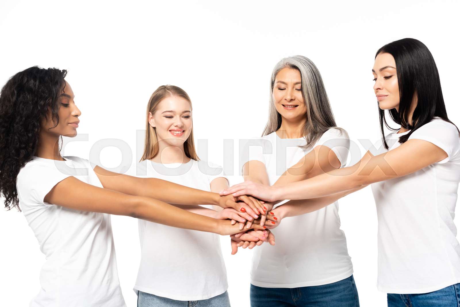 four happy multicultural women putting hands together isolated on white ...