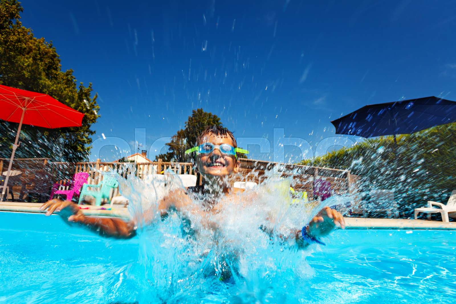 Boy splash jumping into the pool wearing googles | Stock image | Colourbox