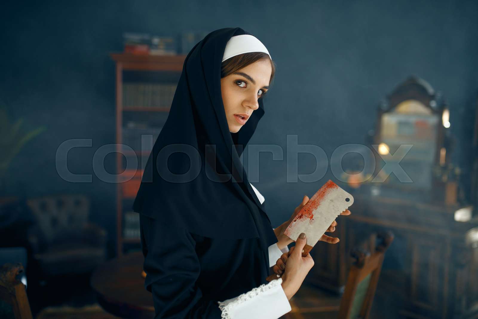 Crazy nun in a cassock holds bloody knife | Stock image | Colourbox