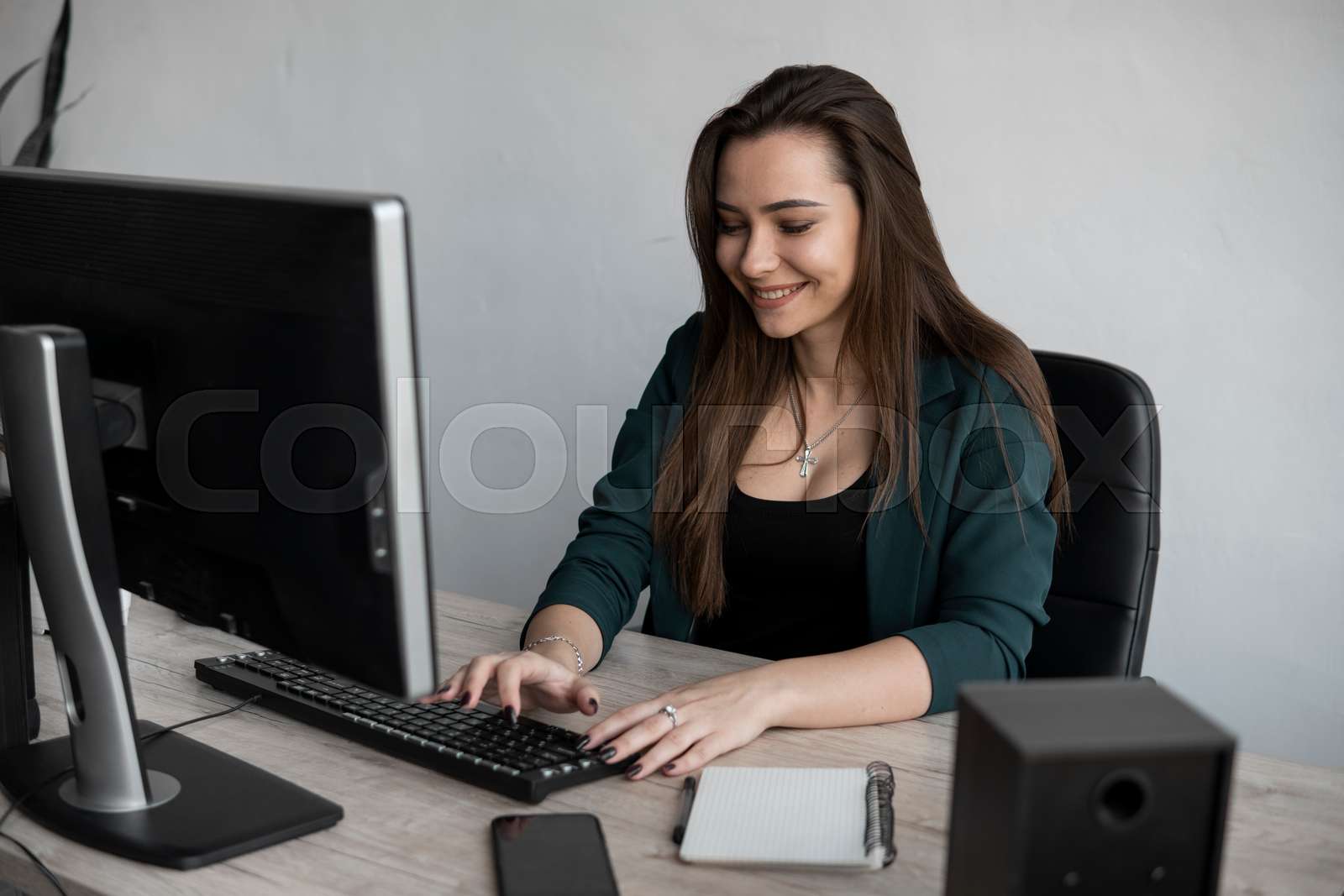 Brunette woman is working in front of a monitor in a office. Business ...