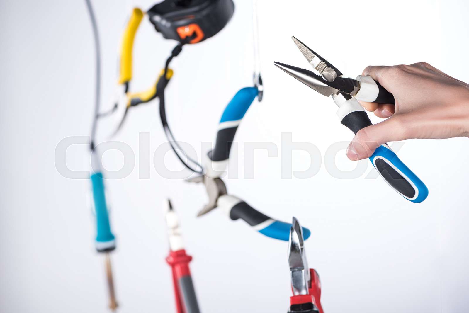 Cropped view of man holding pliers with levitating tools in air ...