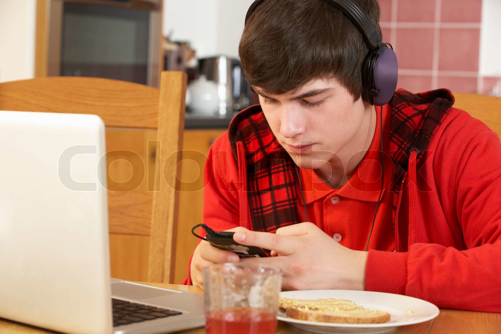Teenage Boy Using Laptop And Listening To MP3 Player Whilst Eating ...