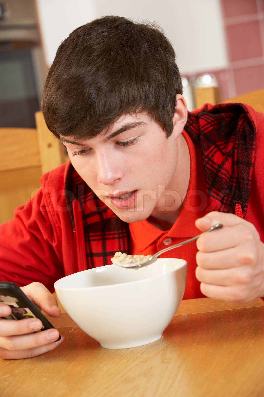 Teenage Boy Teenage Texting Whilst Eating Breakfast | Stock image ...
