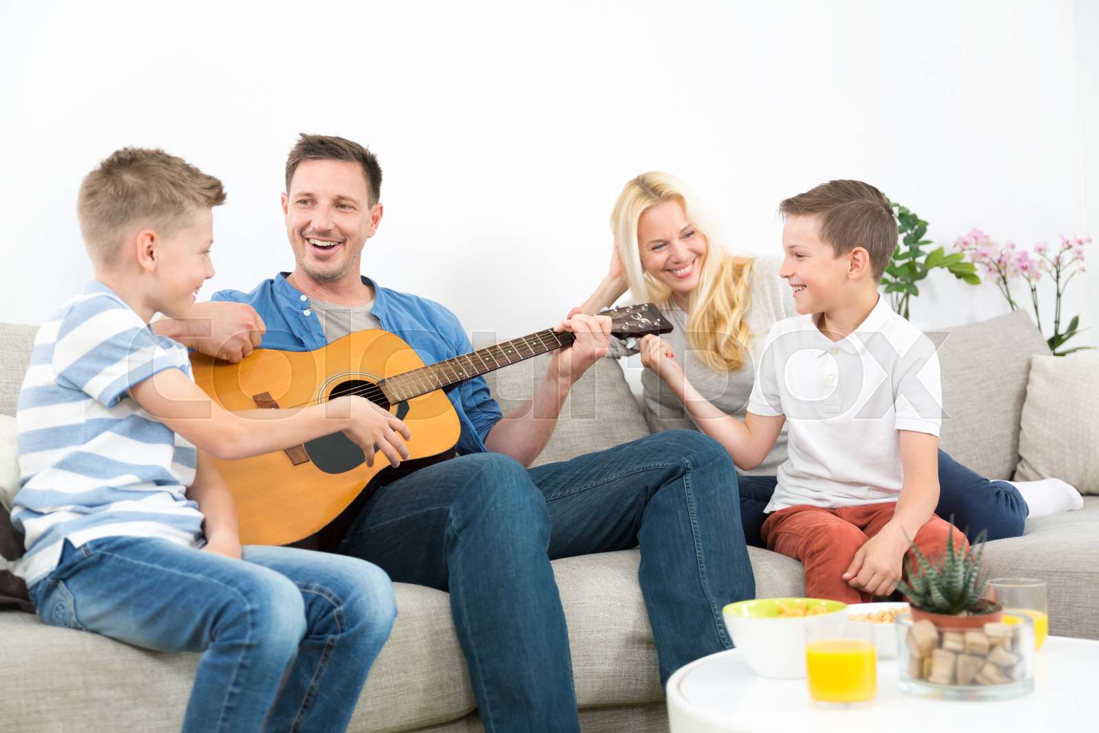 Happy caucasian family smiling, playing guitar and singing songs ...