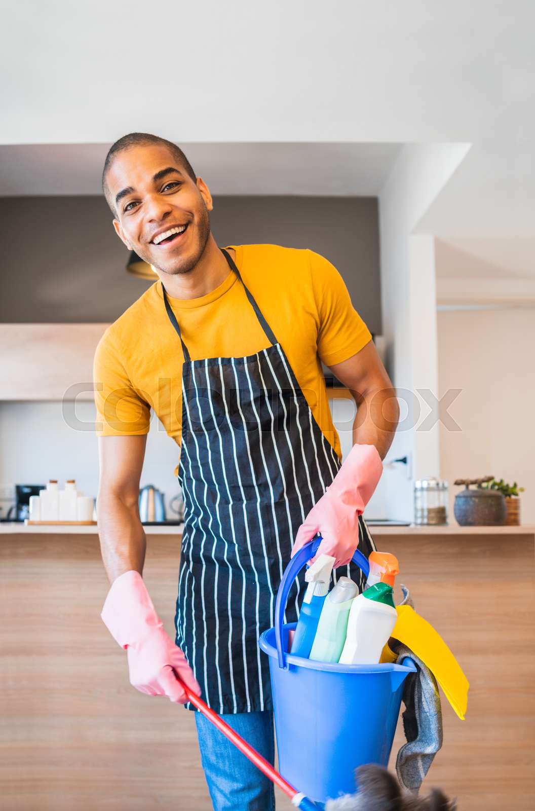 Latin man holding a bucket with cleaning items. | Stock image | Colourbox
