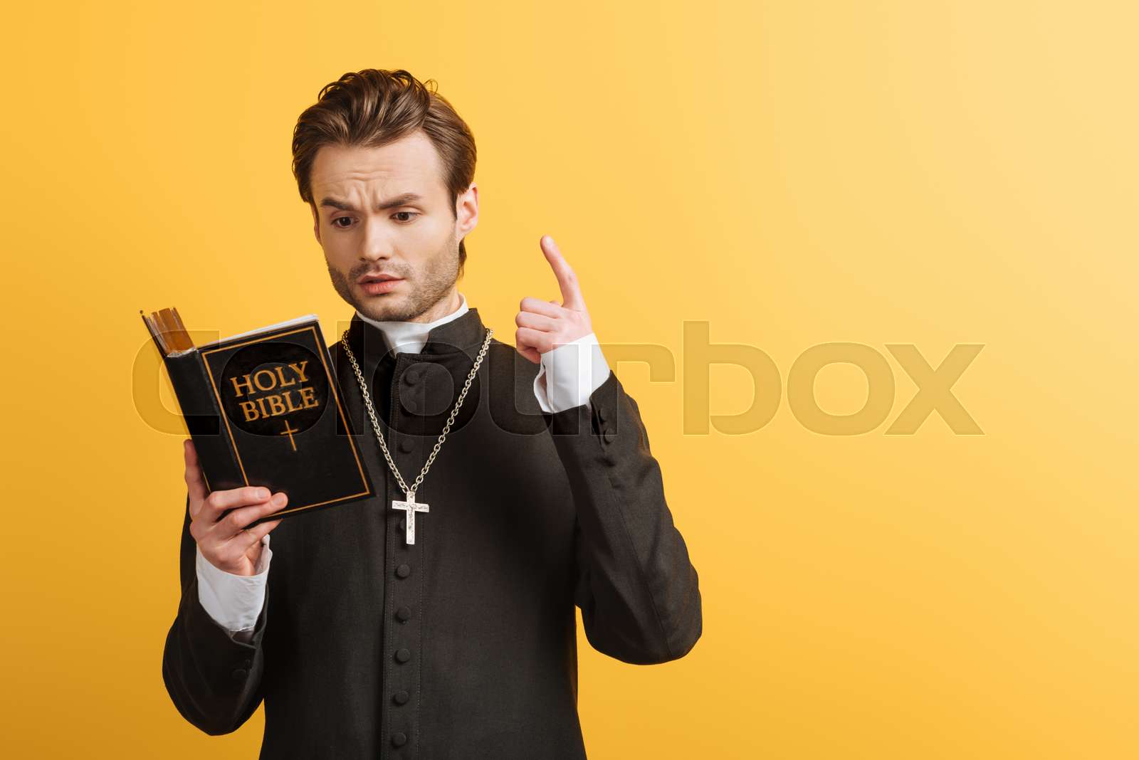 thoughtful catholic priest showing idea sign while reading bible ...
