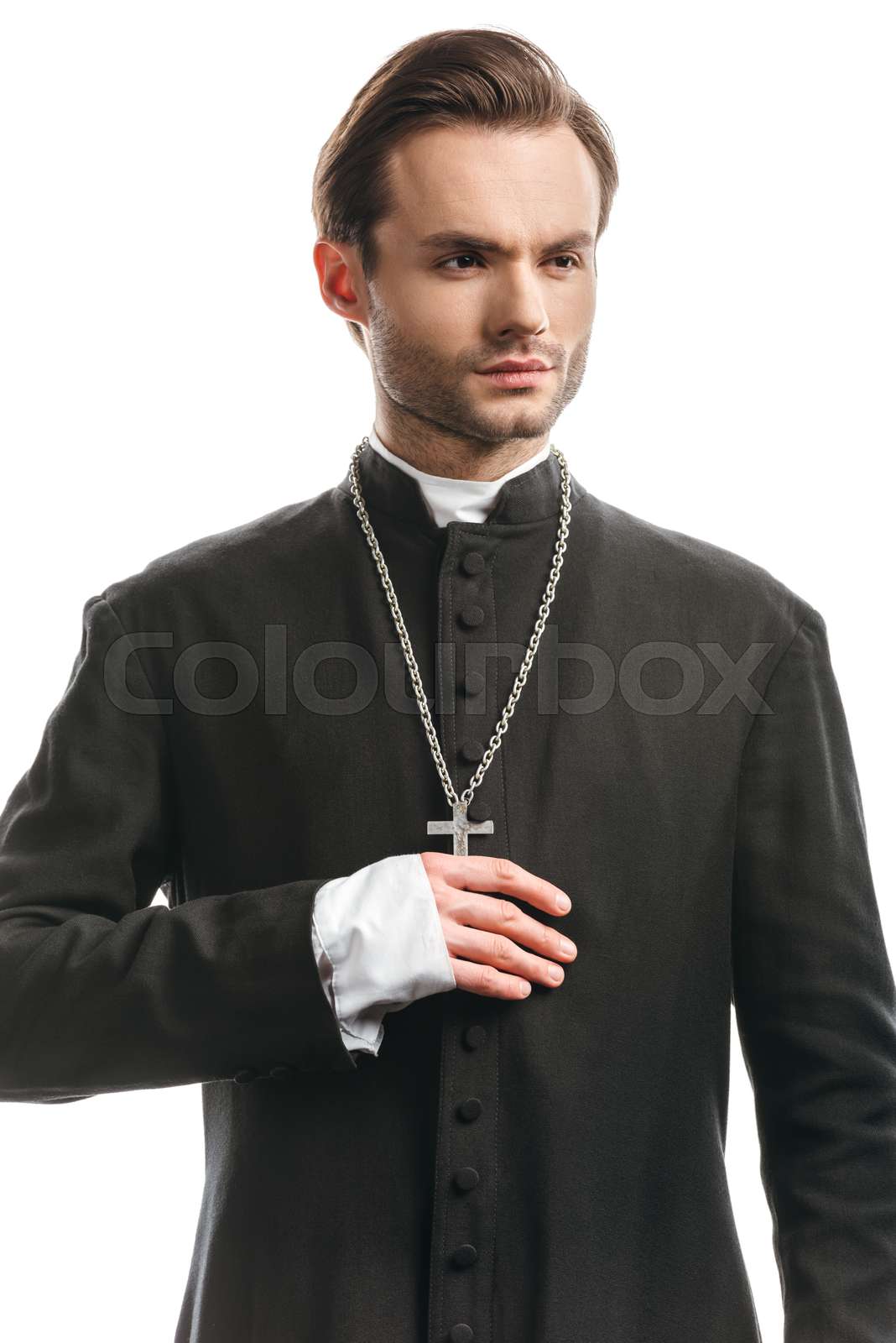 young, confident catholic priest in black cassock looking away isolated ...