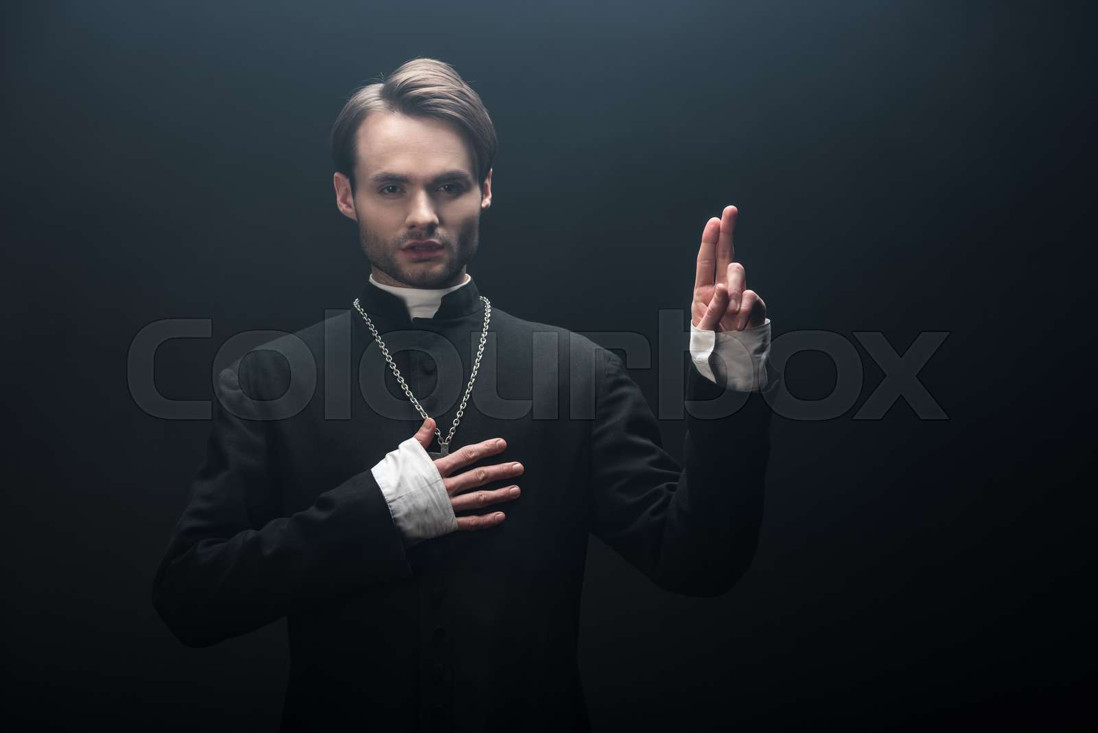 confident catholic priest showing blessing gesture and holding hand on ...