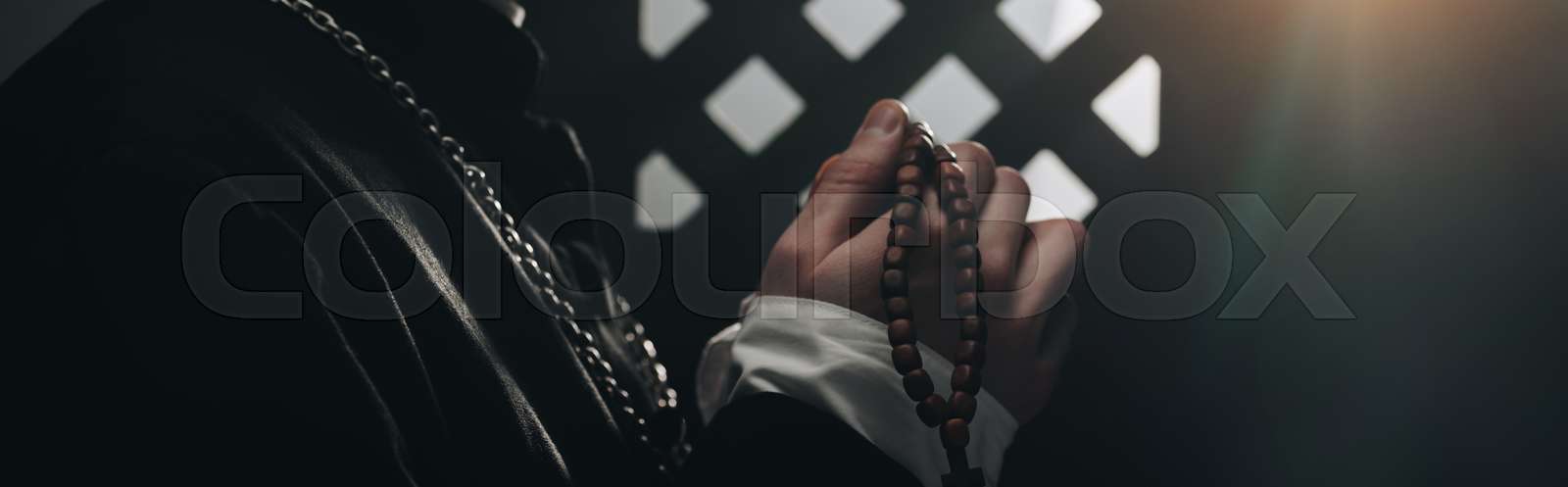 partial view of catholic priest holding wooden rosary beads near ...