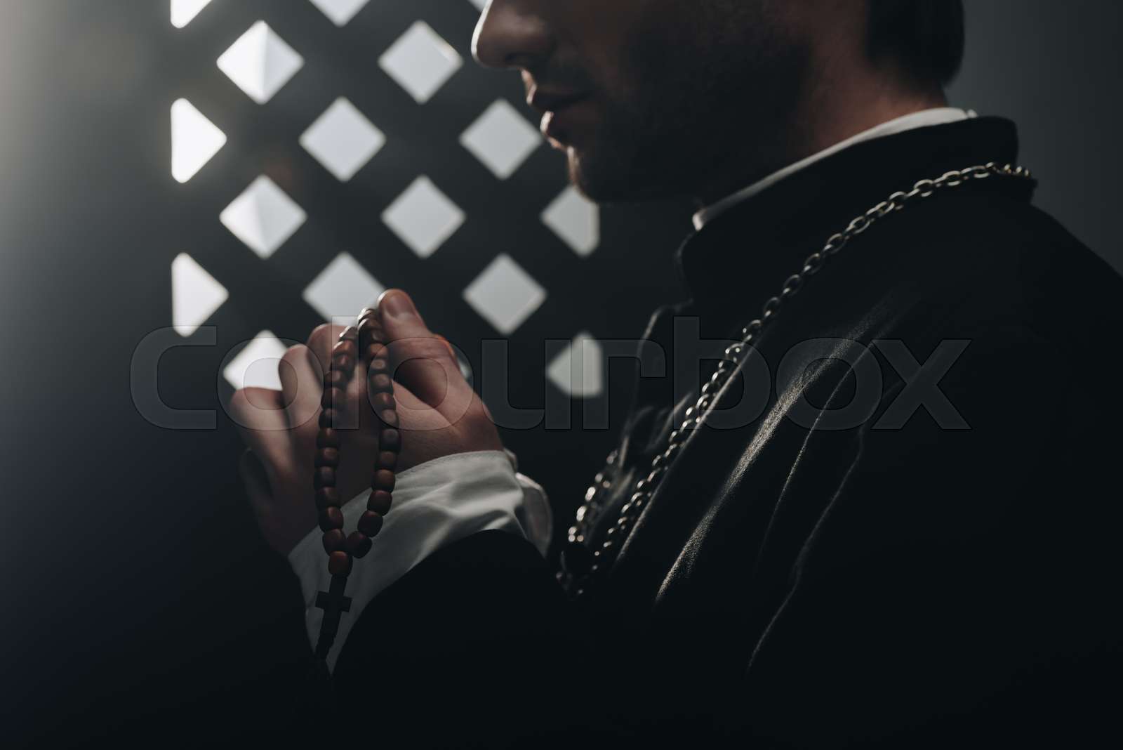 partial view of catholic priest holding wooden rosary beads near ...