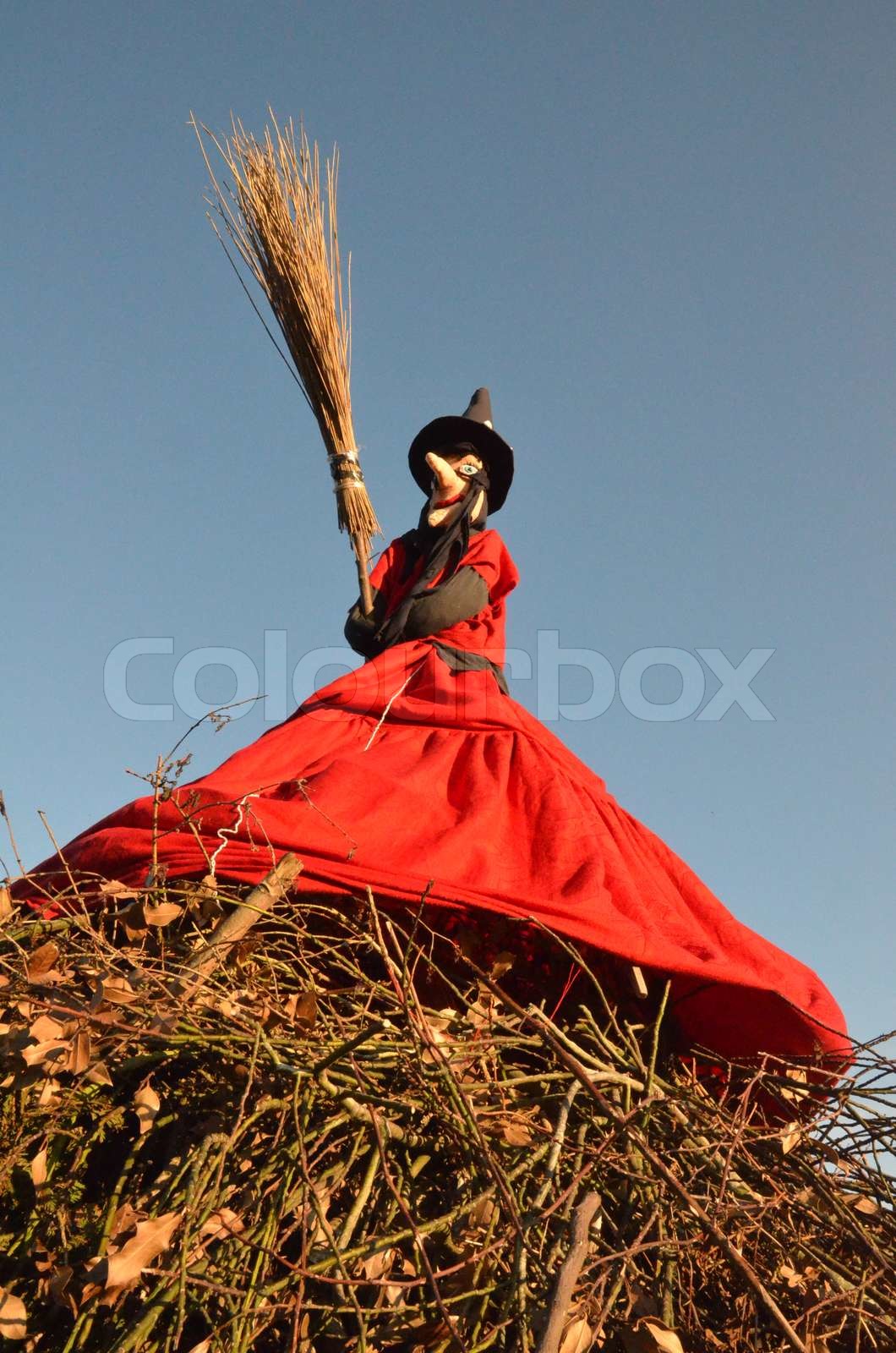 heks i rød kjole med kost på sankt hans bål | Stock foto | Colourbox