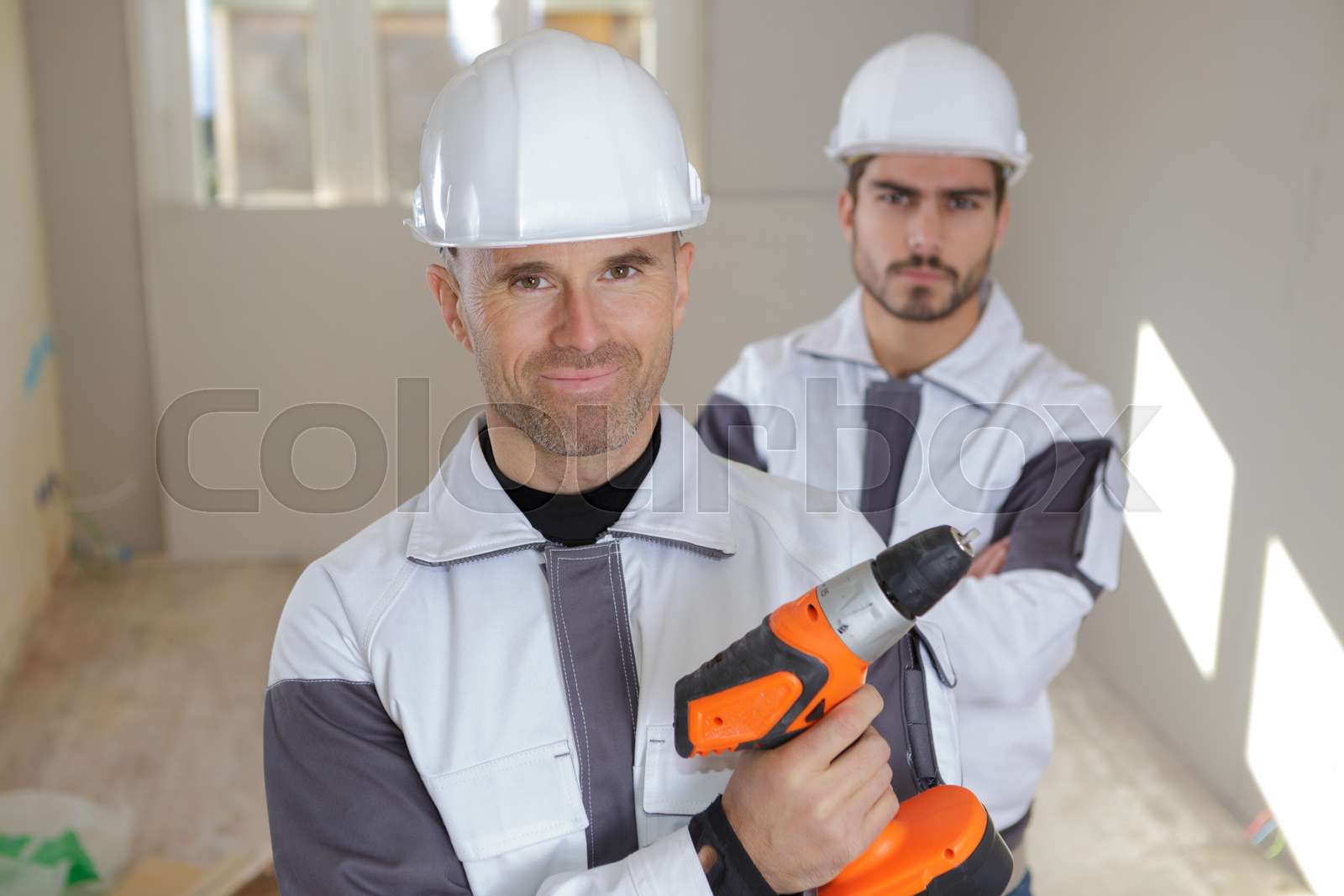 portrait of two male builders in a property under renovation | Stock ...