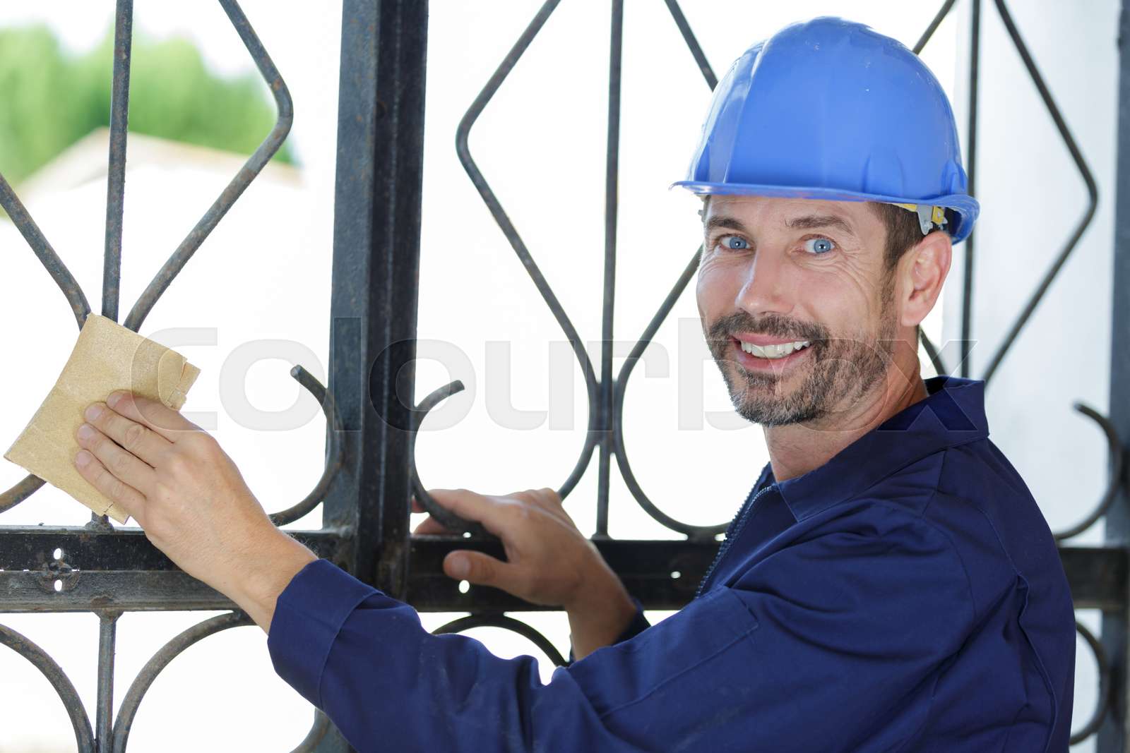 worker sanding a metal fence | Stock image | Colourbox