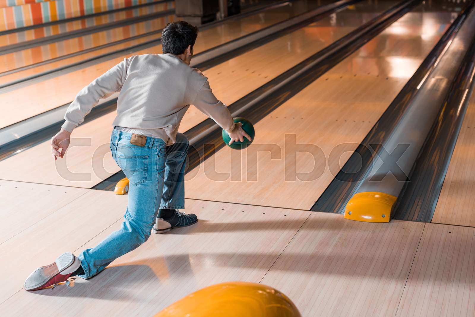 back view of young man throwing bowling ball on skittle alley | Stock ...