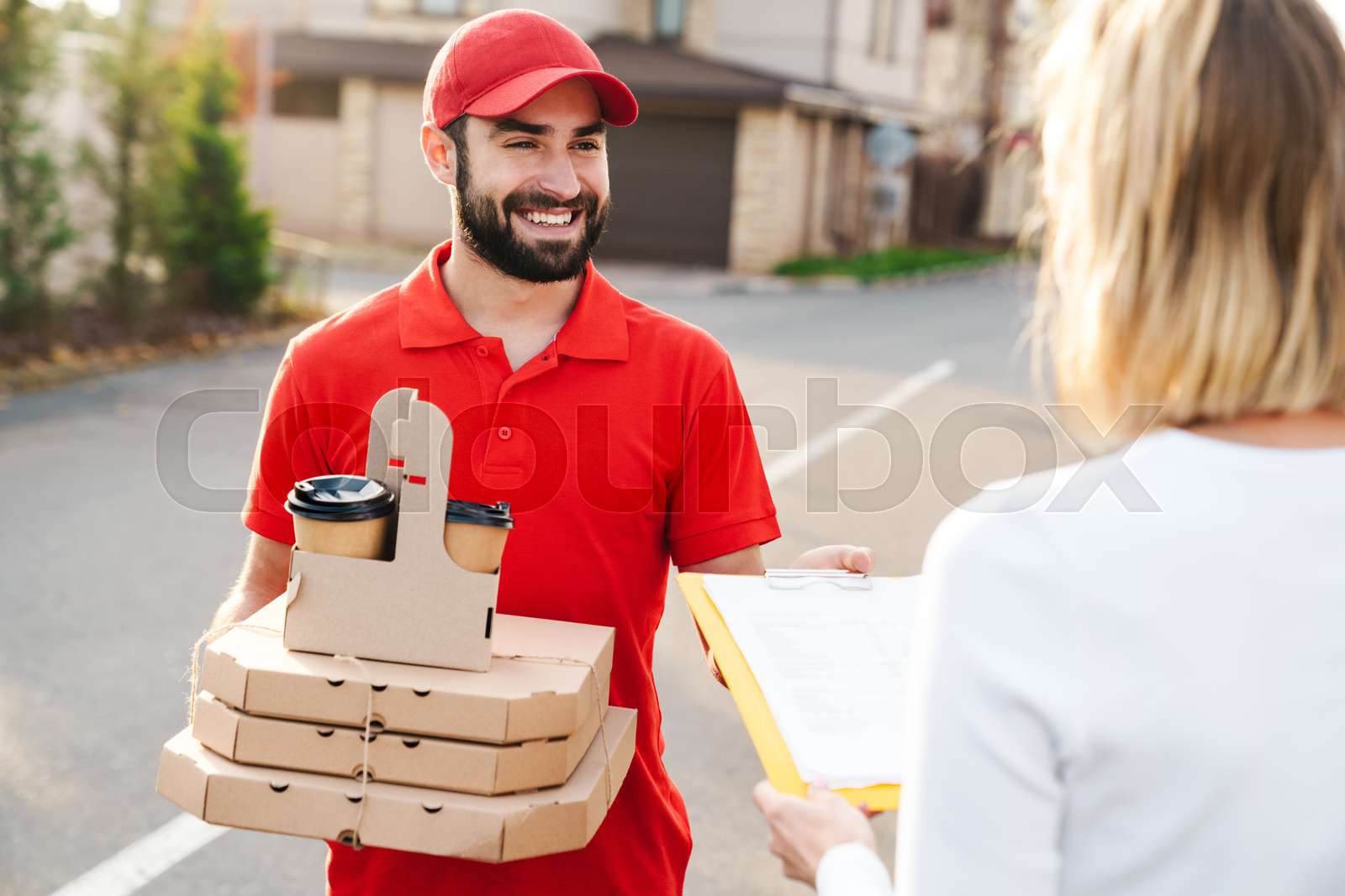 Image of smiling delivery man giving food order to caucasian woman ...