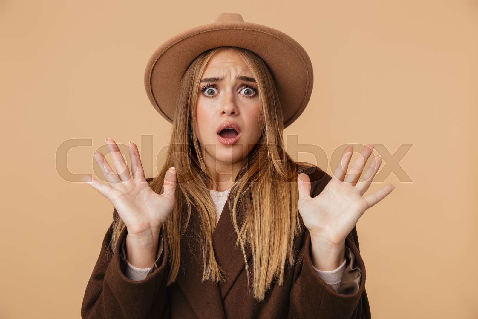 Image of scared girl wearing hat raising her arms and screaming in ...