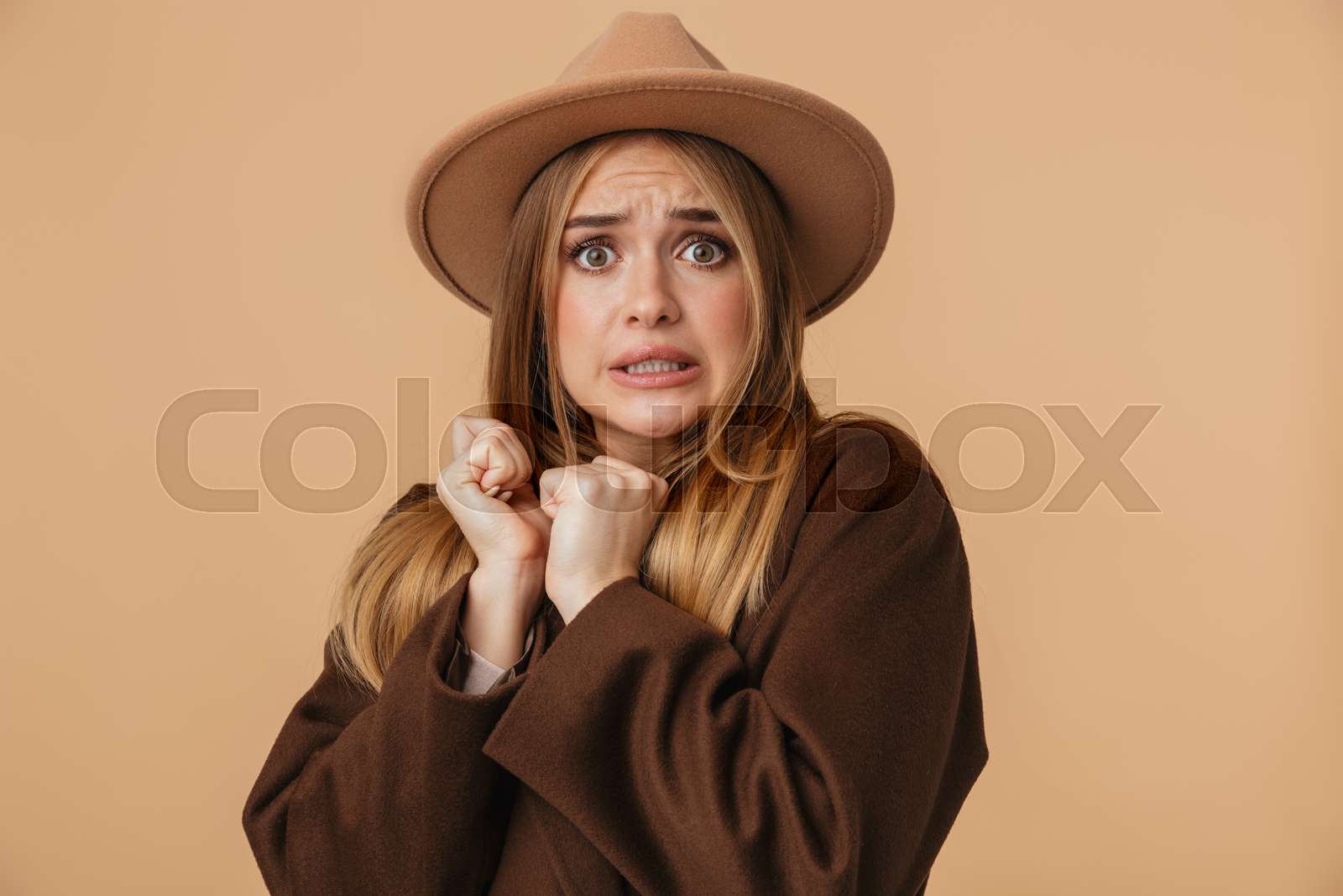 Image of young scared girl wearing hat pressing her arms and expressing ...