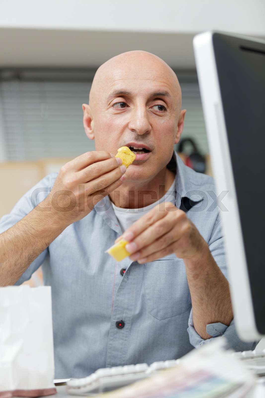 man eating chips in front of computer | Stock image | Colourbox