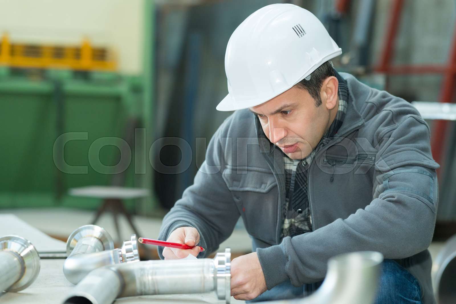 male worker holding pipes in a factory | Stock image | Colourbox