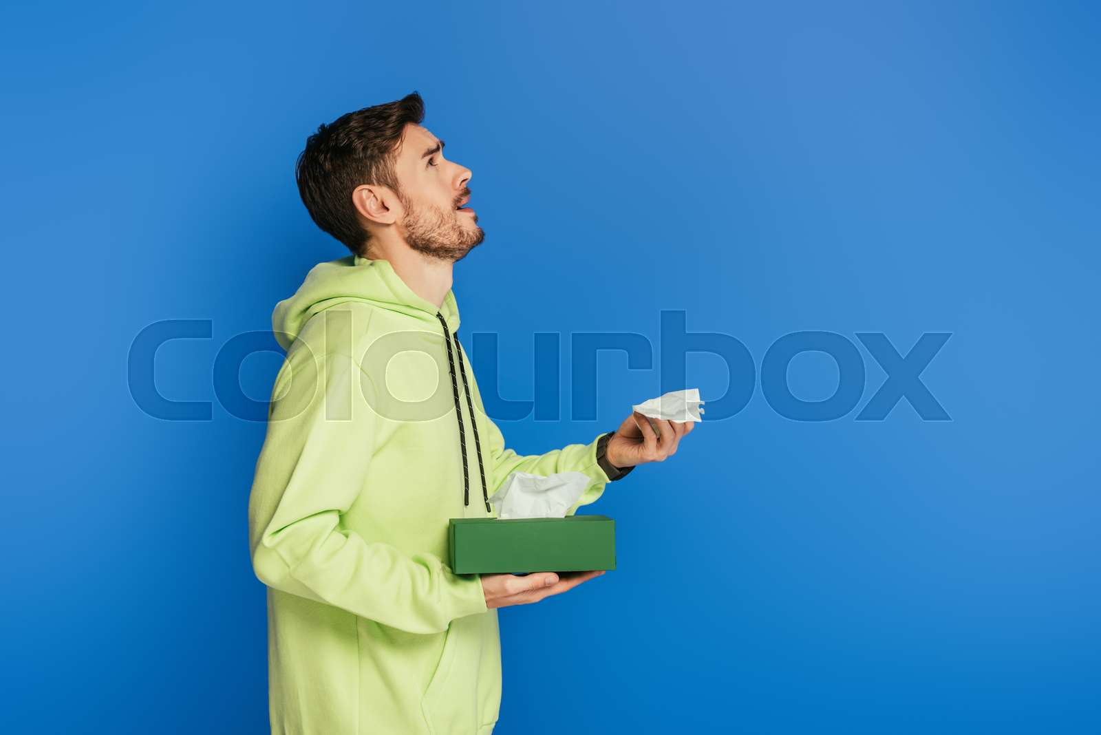 side view of sad man looking up and crying while holding paper napkin ...