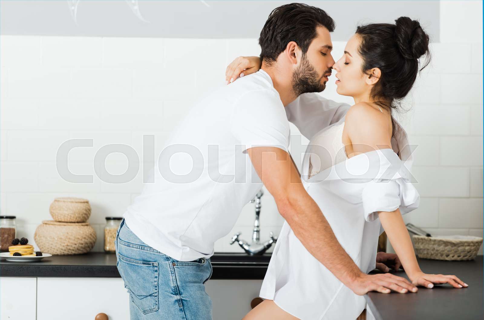 Side View Of Man Kissing Sensual Woman In Bra And Shirt In Kitchen Side View Of Man Kissing Sensual Woman In Bra And Shirt In Kitchen