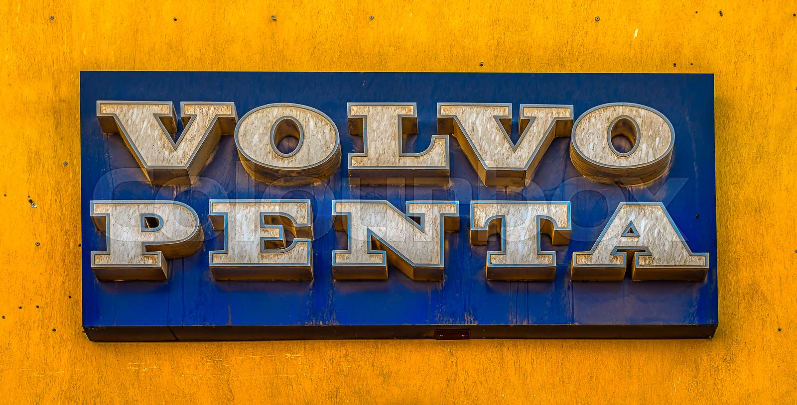 volvo penta, a blue sign with white letters on a yelloow wall | Stock ...