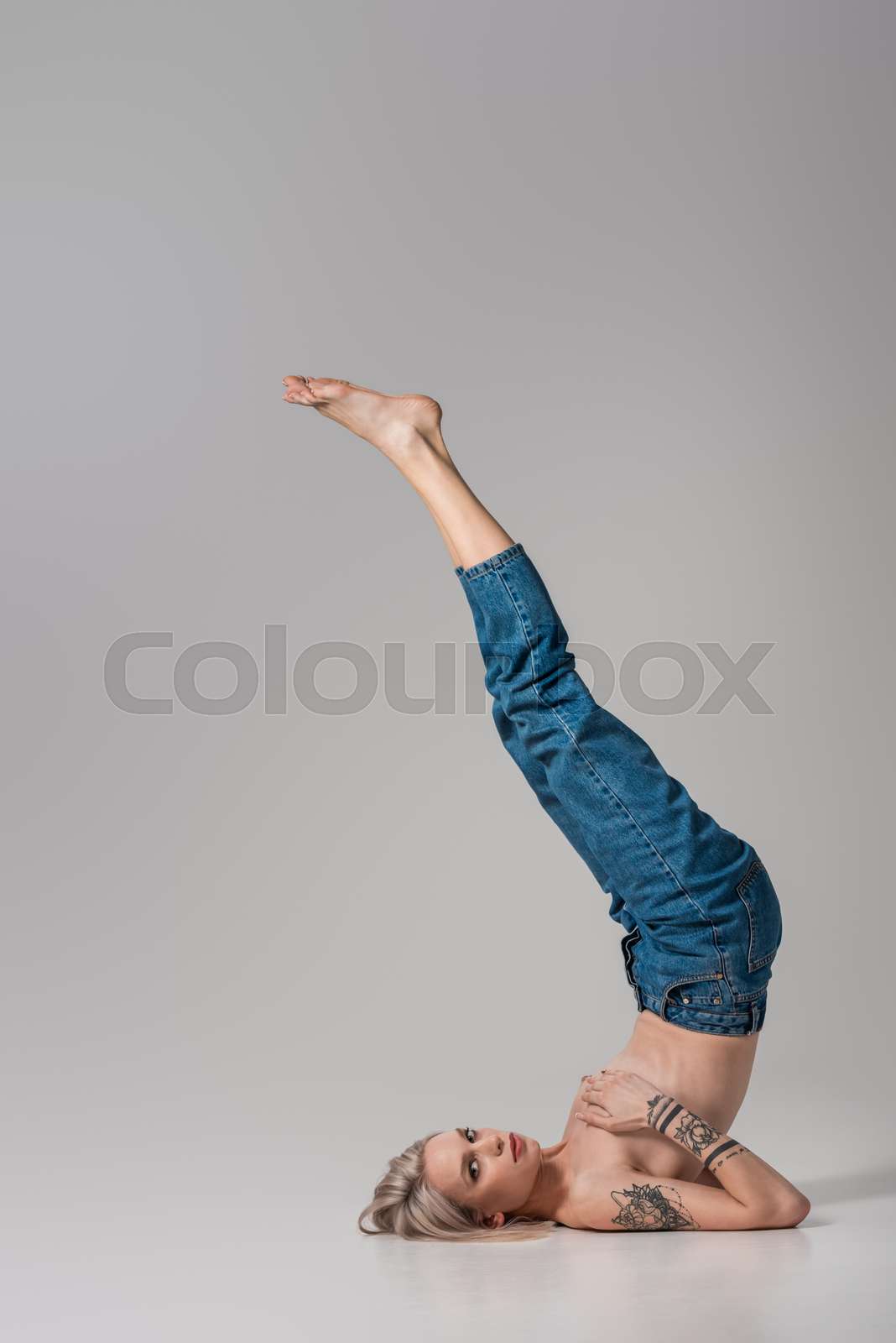 Young Topless Tattooed Girl In Jeans Posing On Floor With Raised Legs