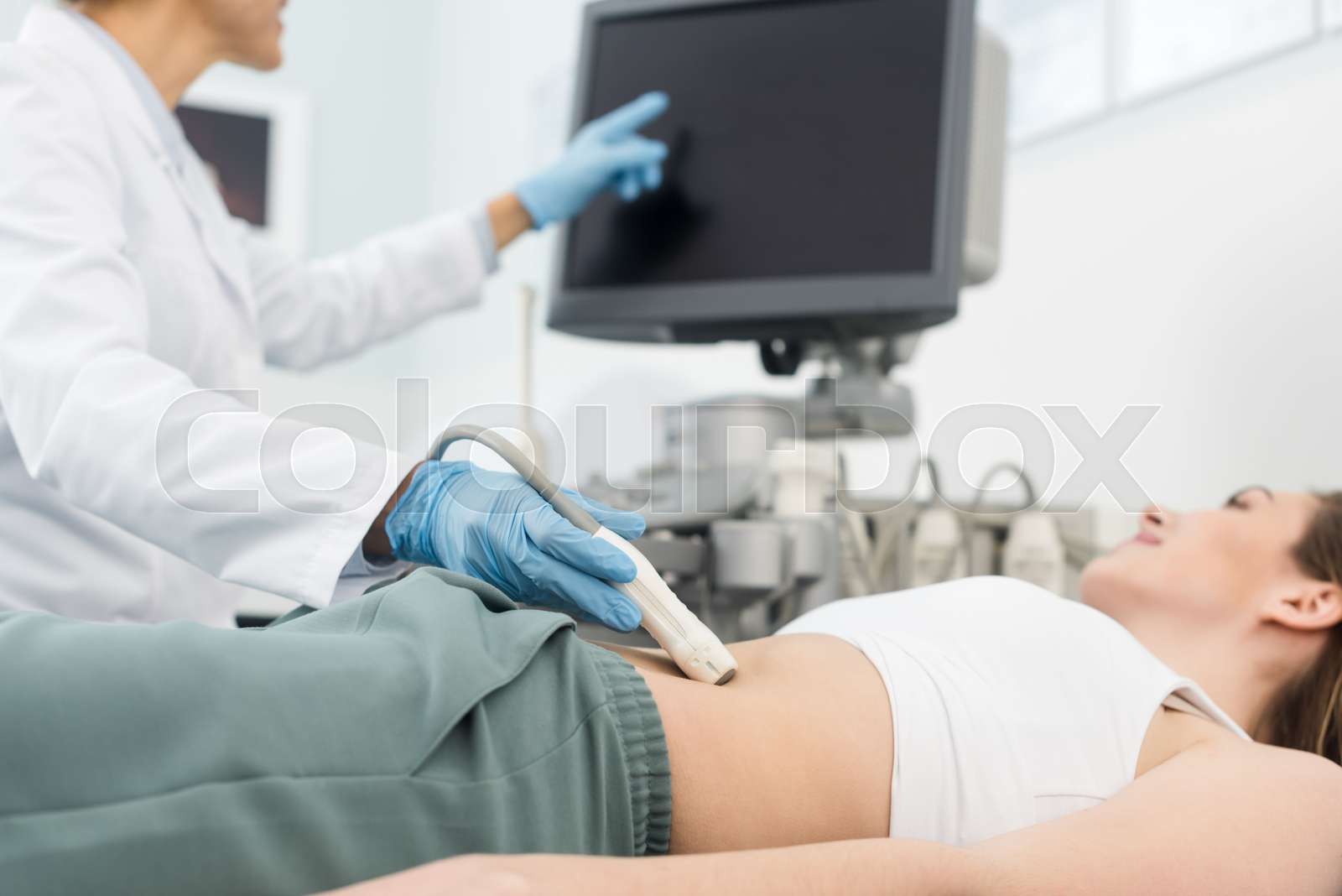 cropped view of doctor making ultrasound scan of stomach and pointing ...