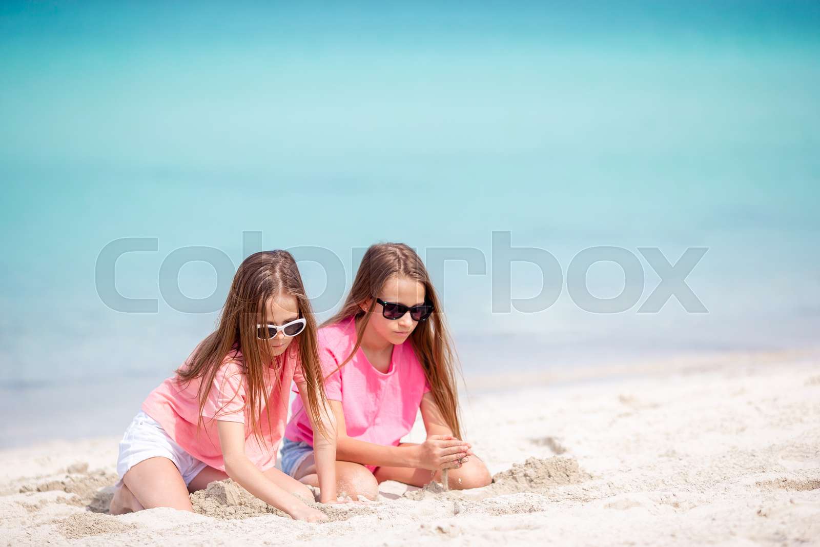 Two Little Happy Girls Have A Lot Of Fun At Tropical Beach Playing
