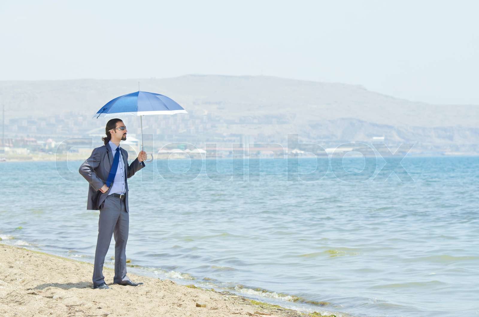 Man with umbrella on seaside beach | Stock image | Colourbox