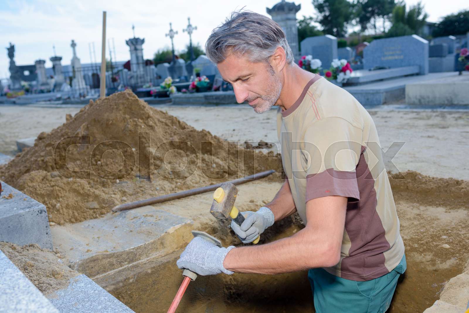 community cemetery worker digging a grave | Stock image | Colourbox