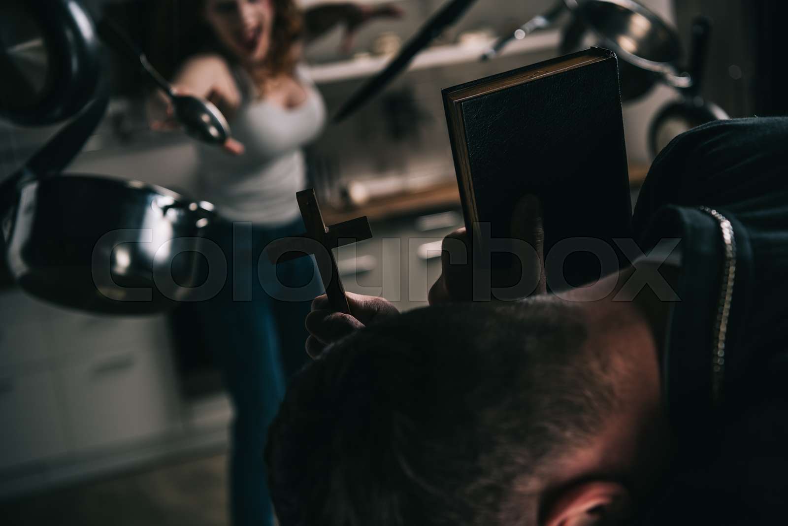 selective focus of demon with levitating cookware and exorcist with ...