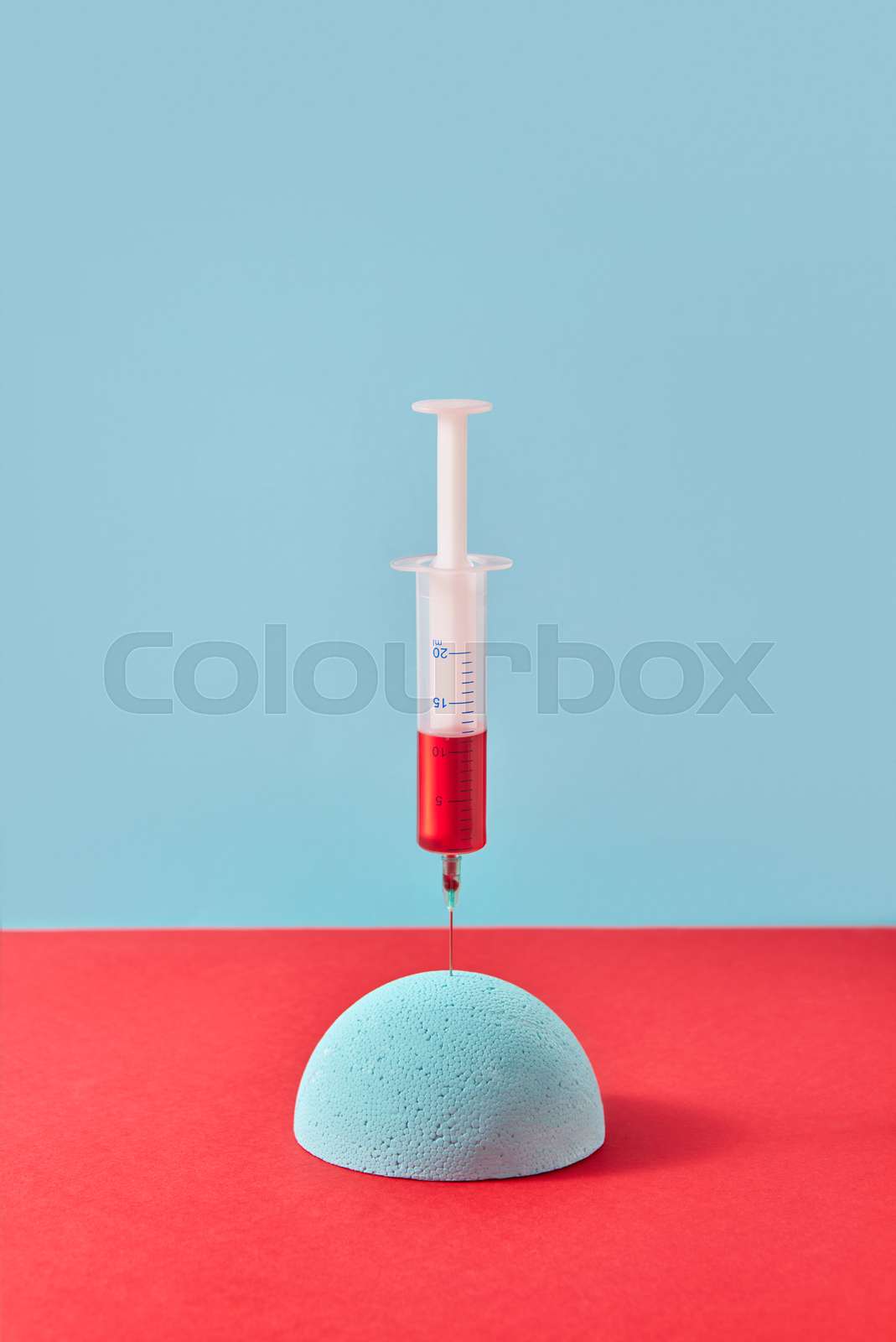 Injection of syringe with red liquid into styrofoam hemisphere. | Stock ...
