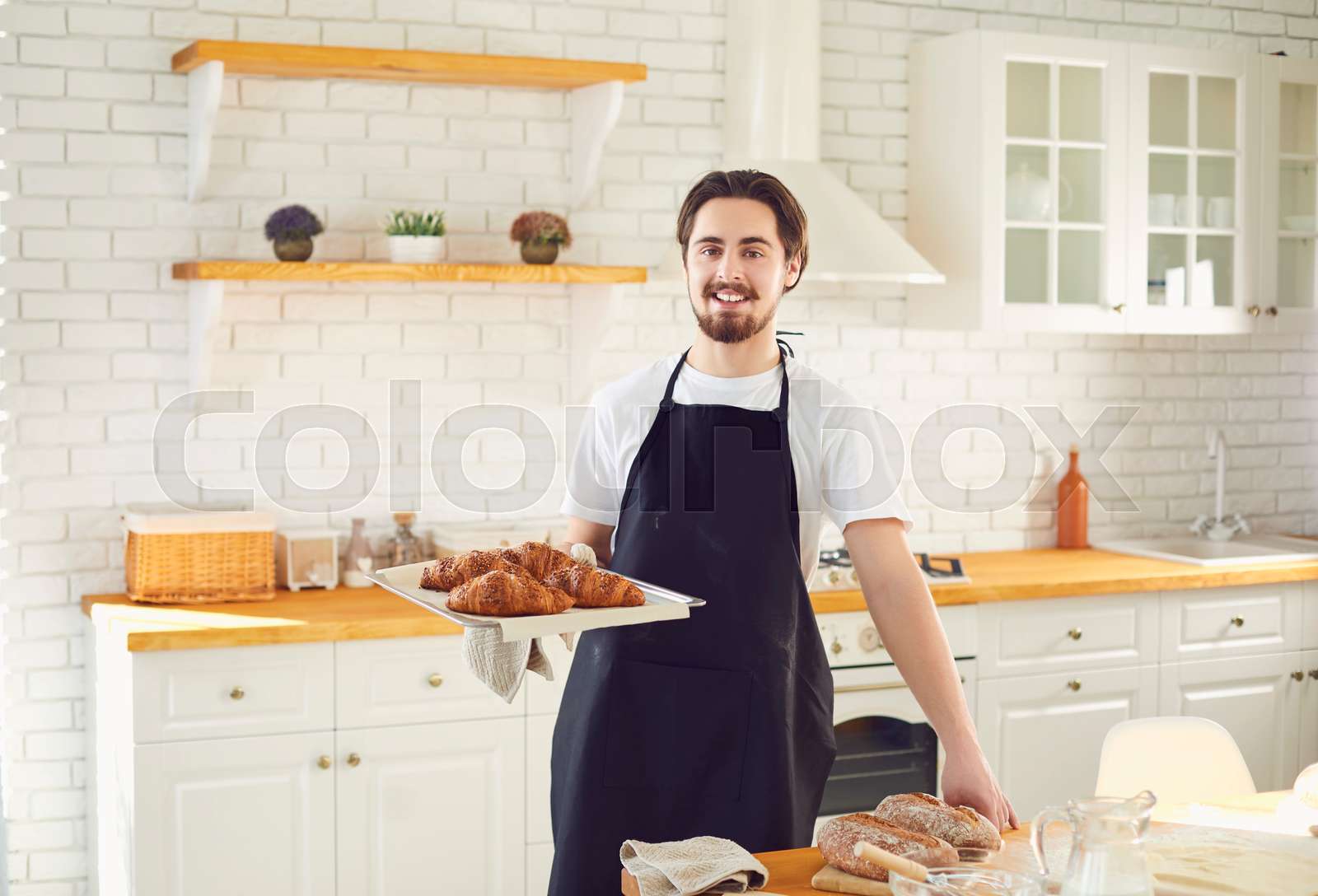 Baker man bearded man smiling holds in his hands a tray with croissants ...