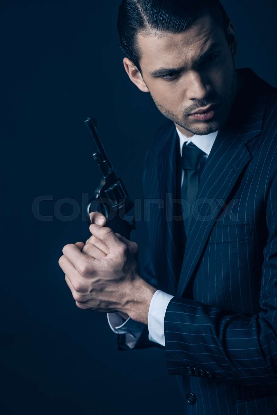 Gangster holding weapon with clenched hands on dark blue | Stock image ...