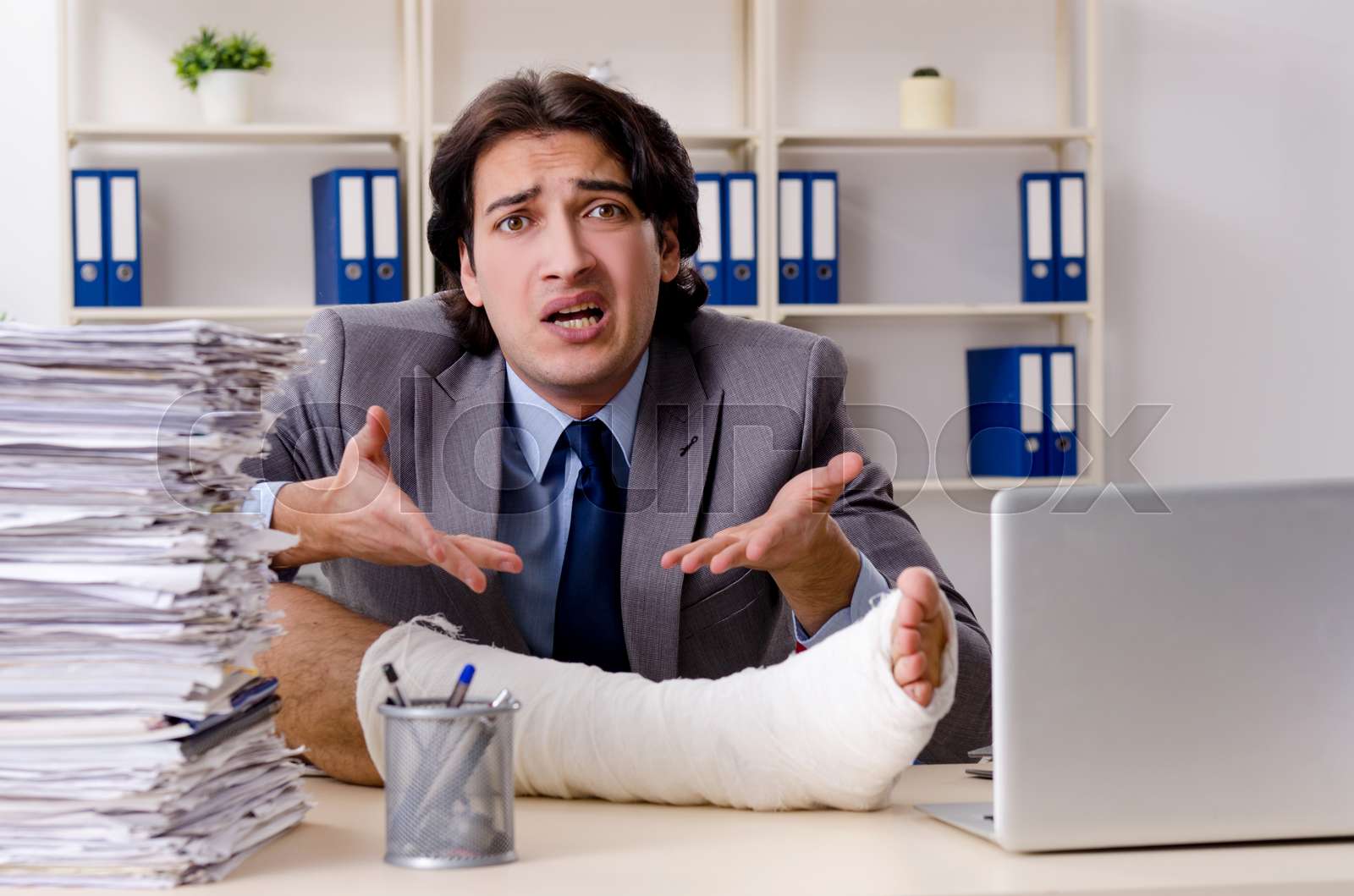 Leg injured employee working in the office | Stock image | Colourbox