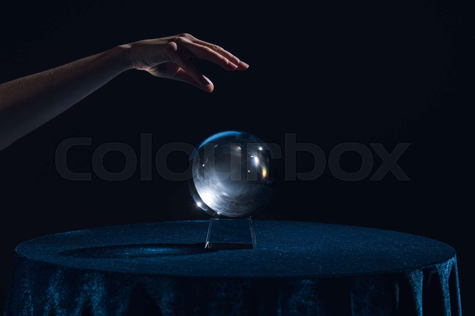 Cropped view of female hand above crystal ball on table isolated on ...