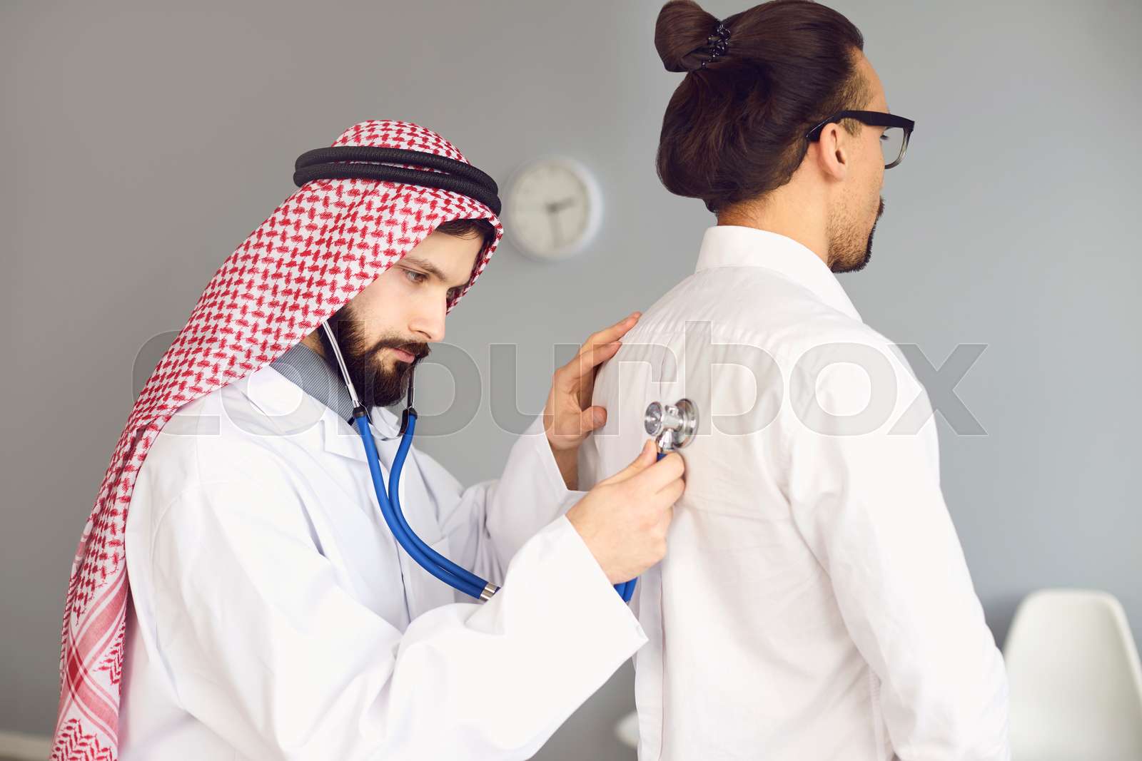 Arab doctor male listens in a stethoscope to a patient in a clinic ...