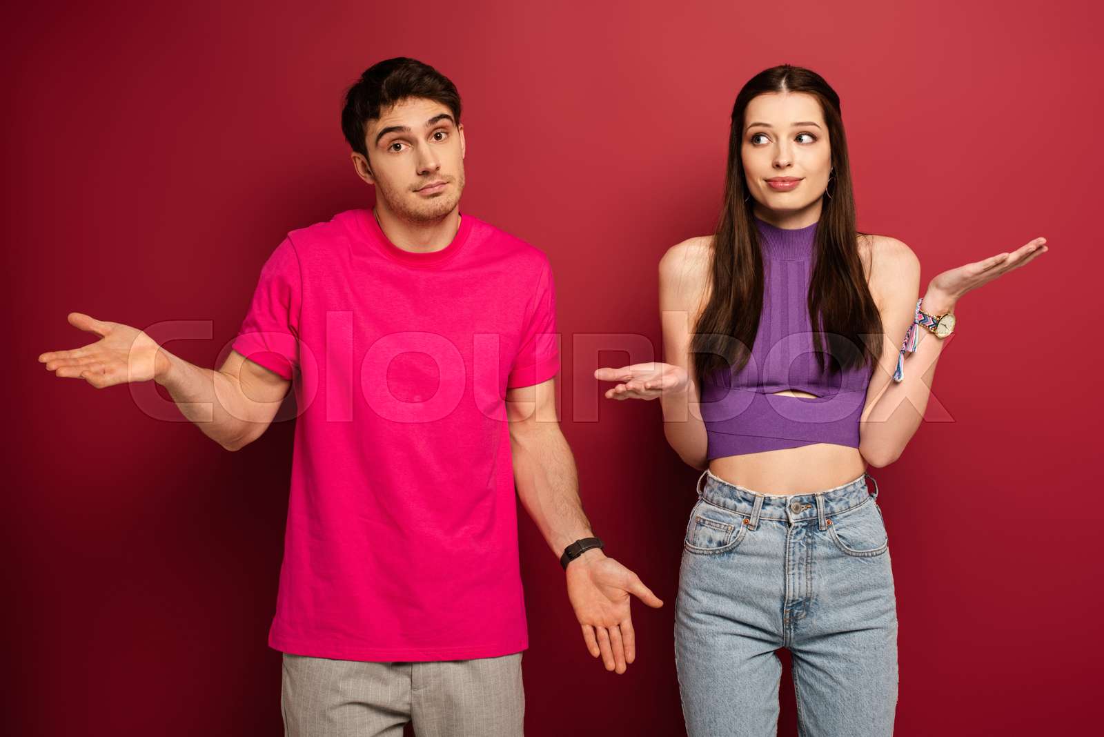 confused young couple with shrug gestures on red | Stock image | Colourbox
