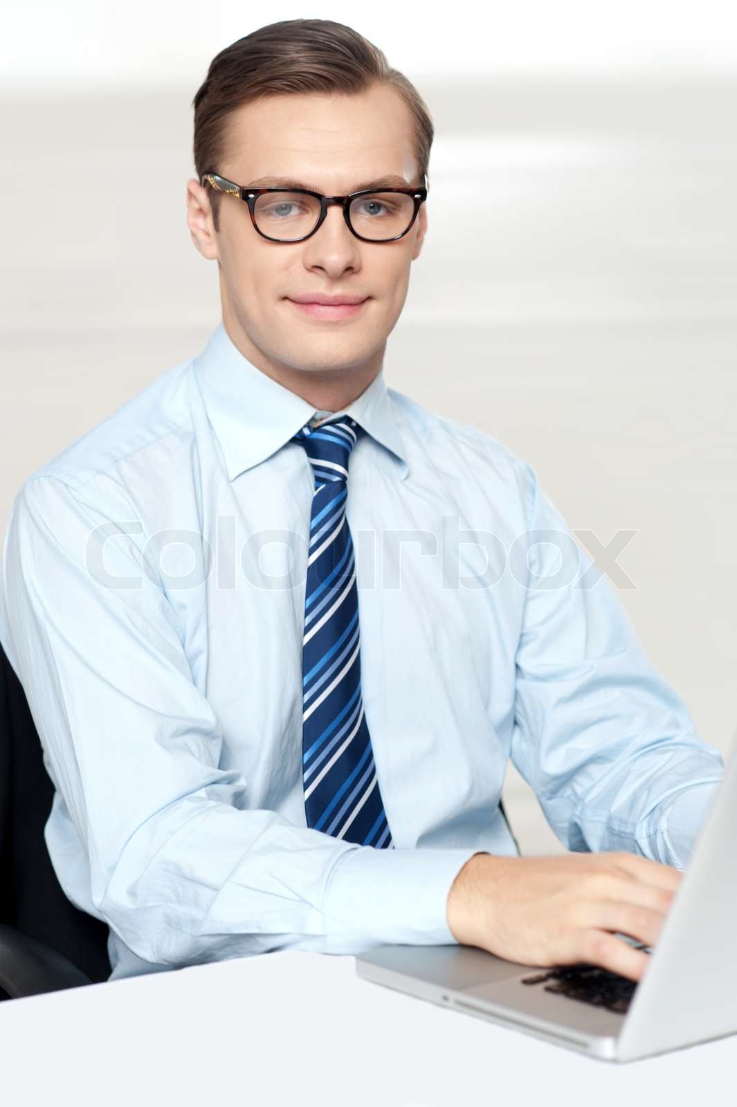 Man sitting on chair using laptop in office | Stock image | Colourbox