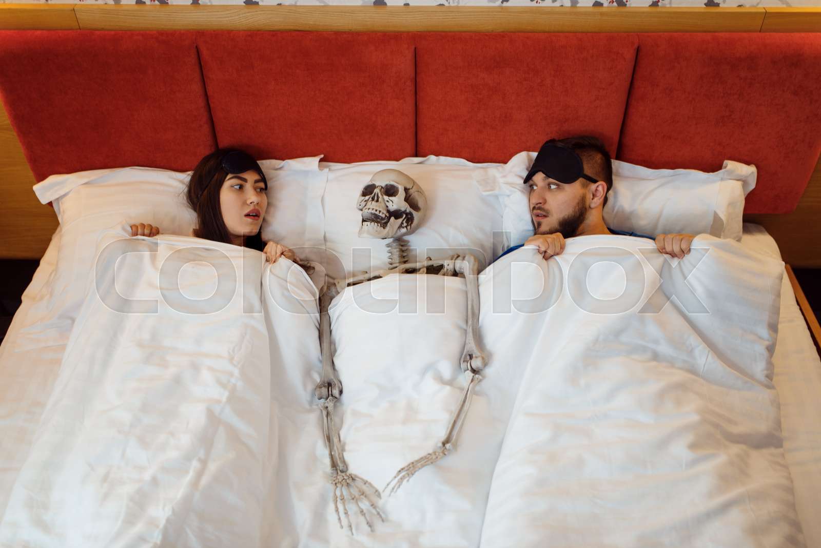Husband, wife and skeleton lying in the bed | Stock image | Colourbox